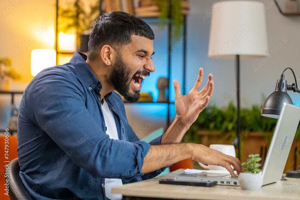 Stock-Foto „Angry furious Indian man freelancer using laptop while ...