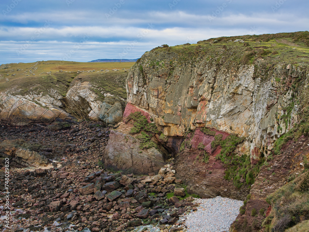 Colourful coastal cliffs on the Wales Coast Path. The rocks are of the ...