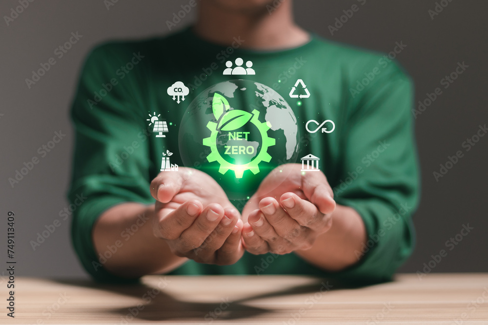 Net zero and carbon neutral concept. Person holding globe with net zero icon on virtual screen ...