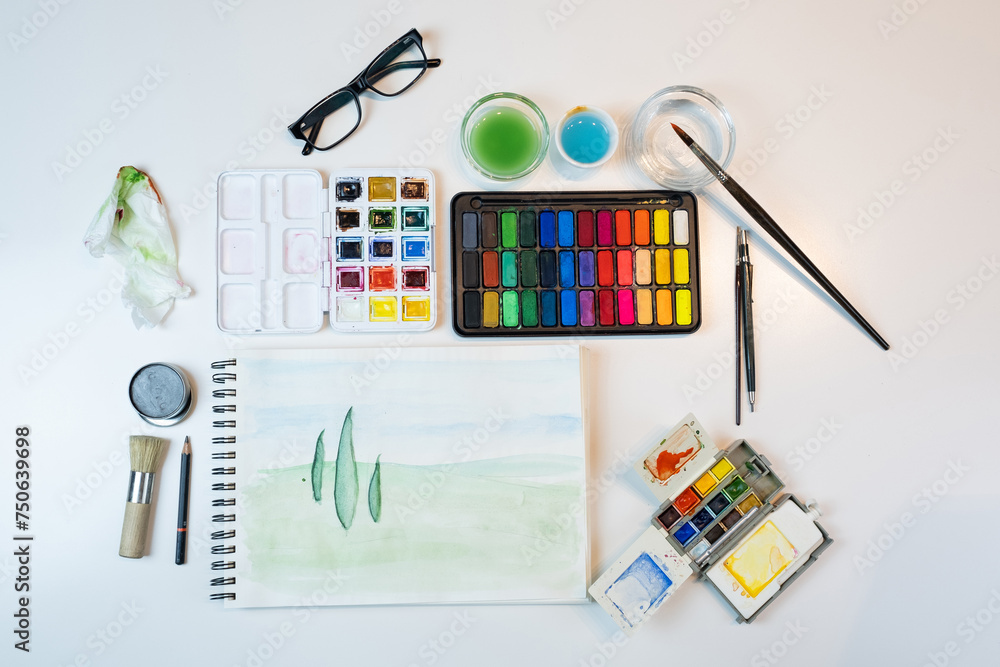 Watercolor materials arranged on a white table, working utensils ...