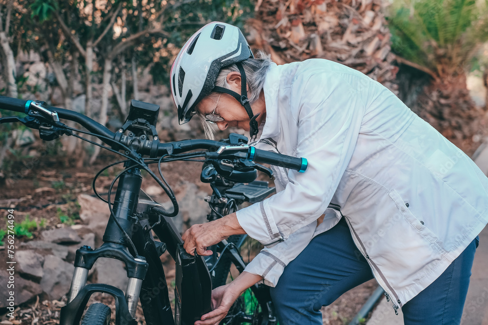 Sporty senior woman with helmet in outdoors activity with electric ...