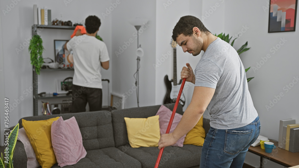 Two men cleaning and organizing a modern living room in a shared ...