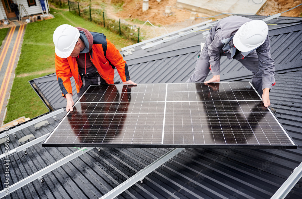 Electricians installing solar panel system on roof of house. Men ...