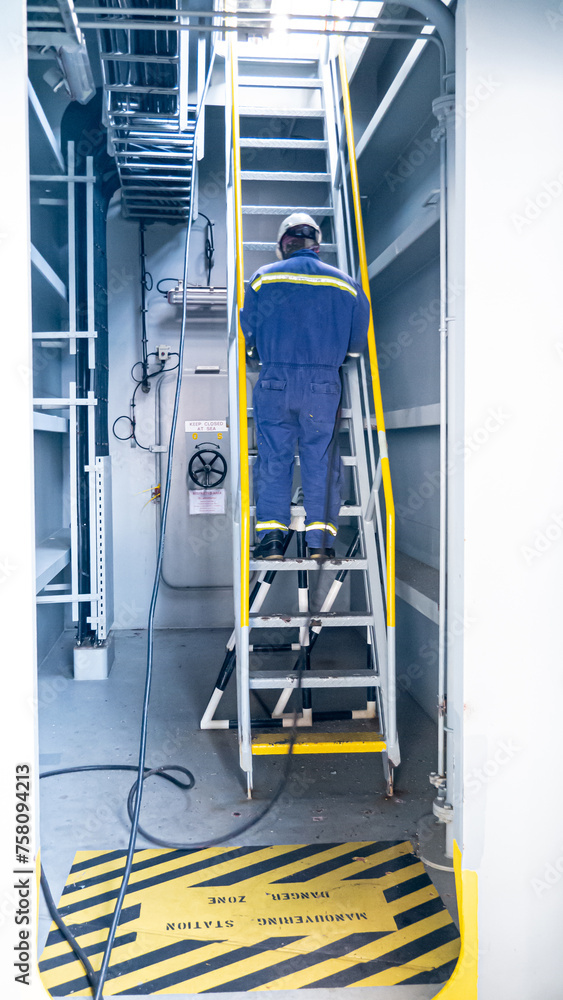 Able seaman crew member of cargo vessel is chipping rust from the ship ...