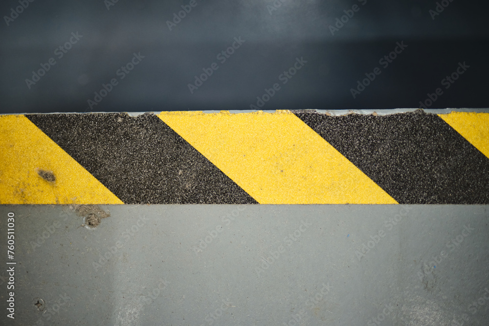 A black and yellow hazard warning barrier in an industrial setting ...