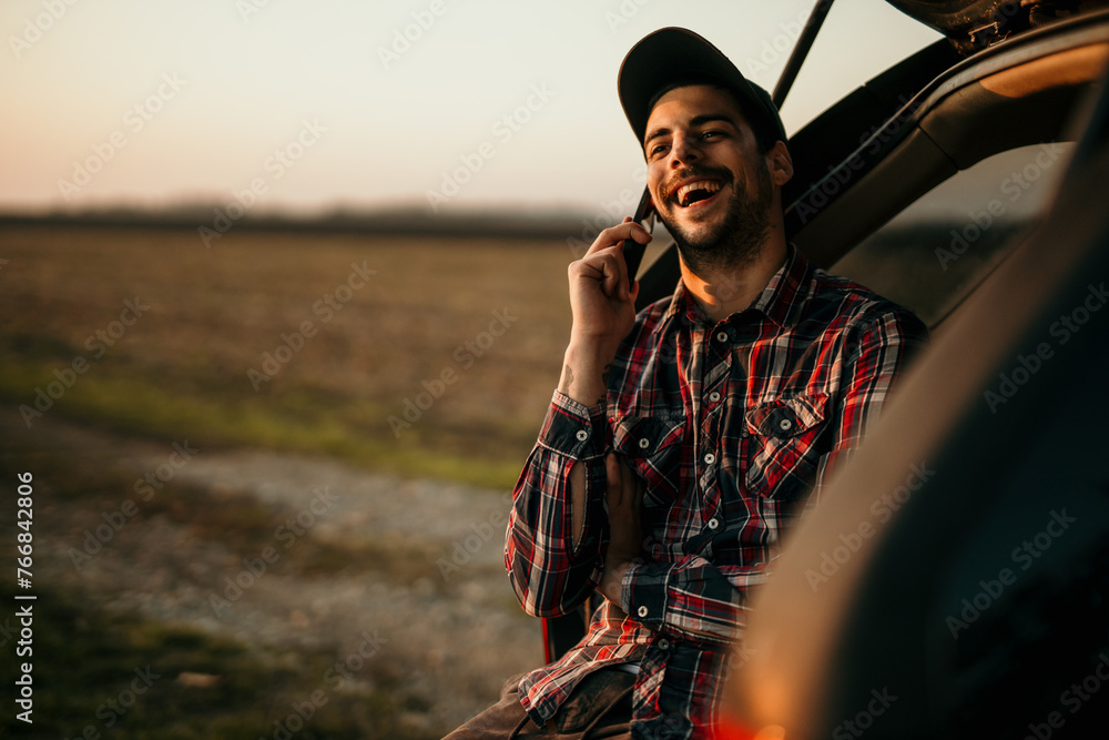 Guy utilizing his car as a mobile workstation, seizing the moment to ...