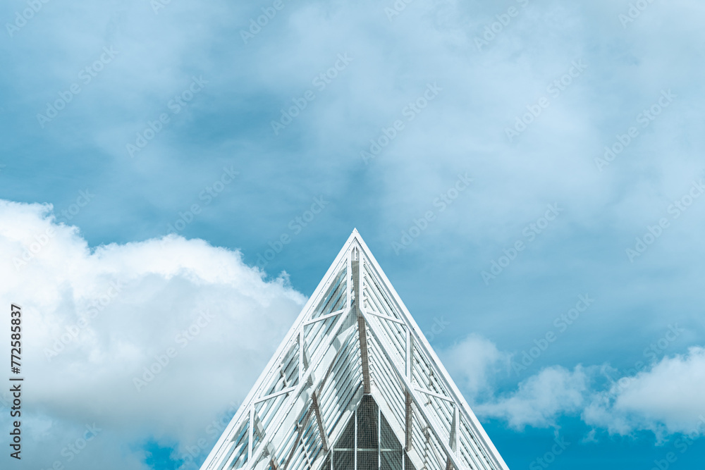 The top of a pyramid-shaped roof made up of metal frames and glass. The ...