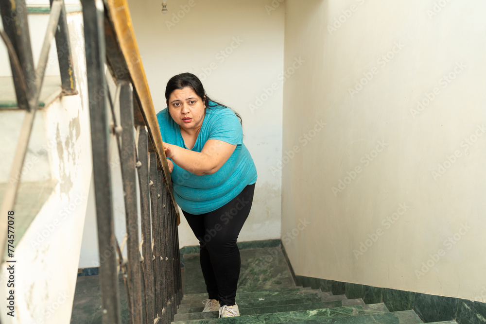 Exhausted tired overweight indian woman have difficulty climbing stairs ...