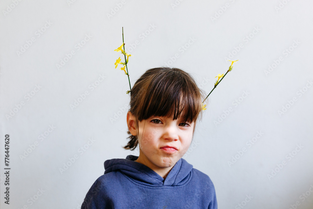 portrait of funny little girl with flowers on top of the head making ...