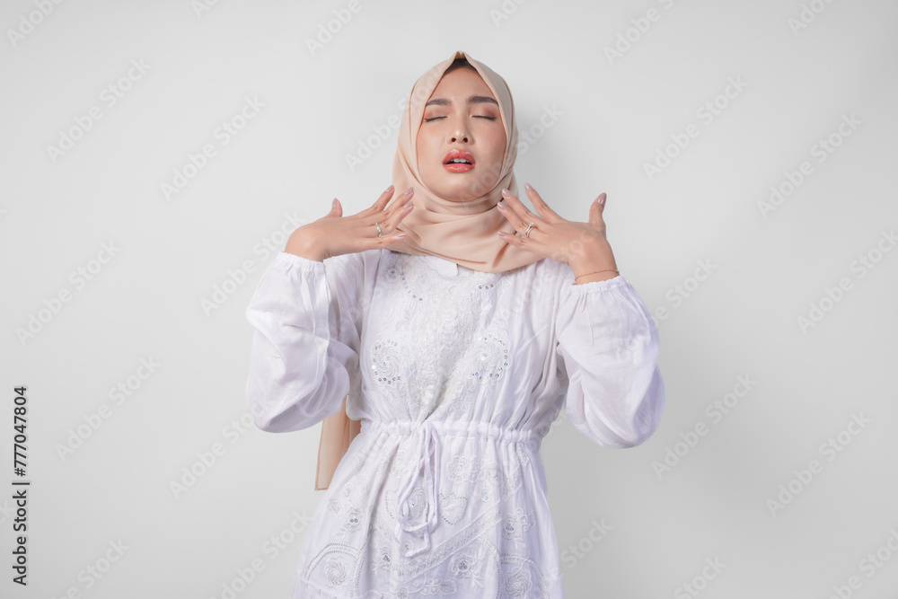 Young Asian Muslim woman in white dress and hijab raising hand to fan ...
