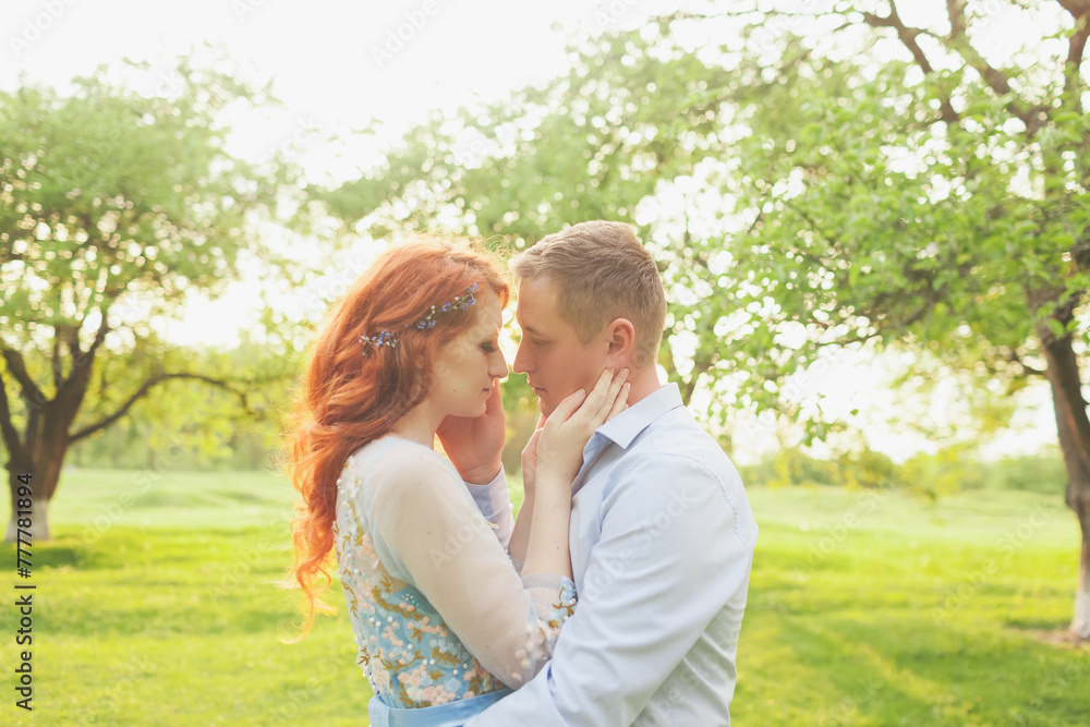 young couple in love kissing. woman with fiery hair in a blue dress ...