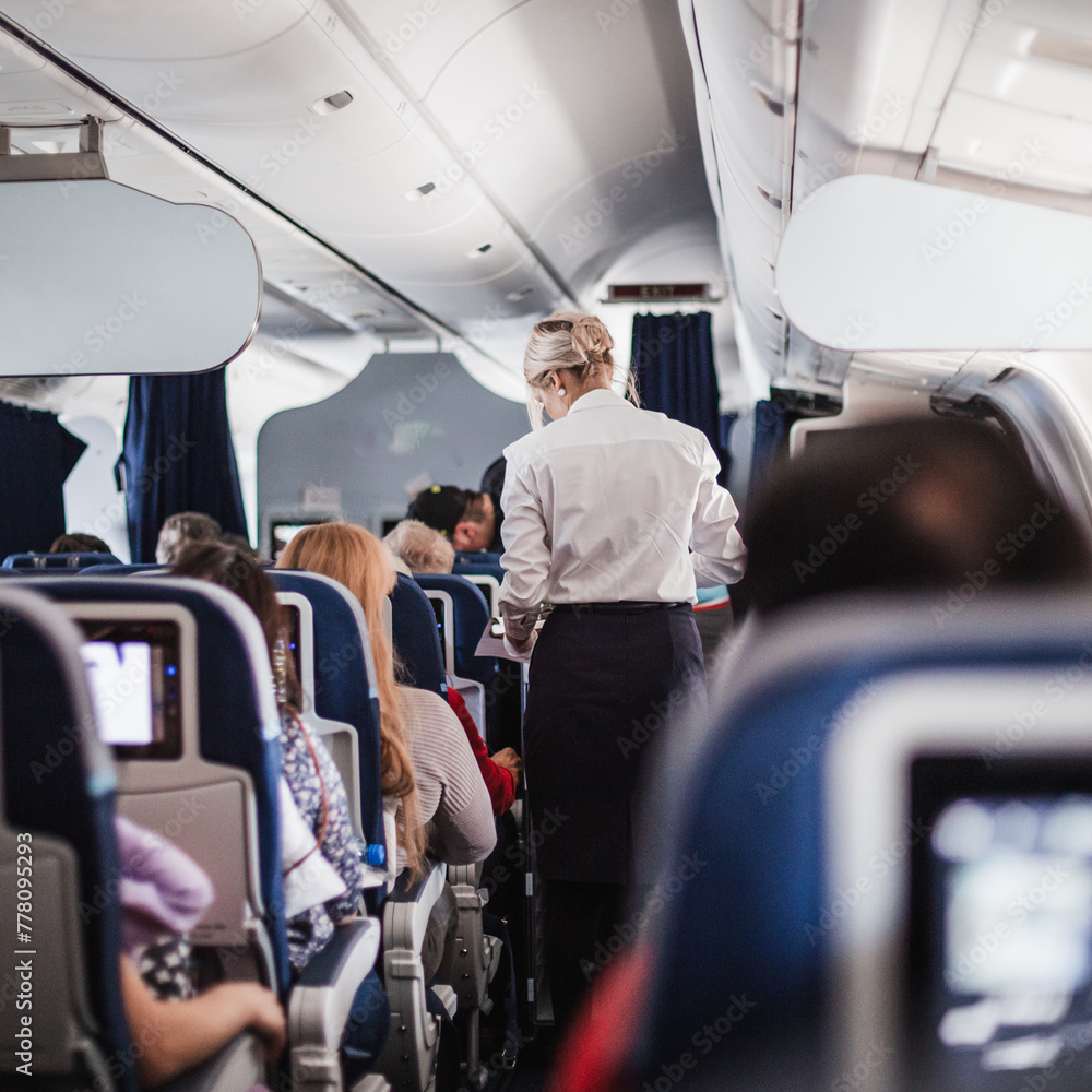Interior of airplane with passengers on seats and stewardess in uniform ...