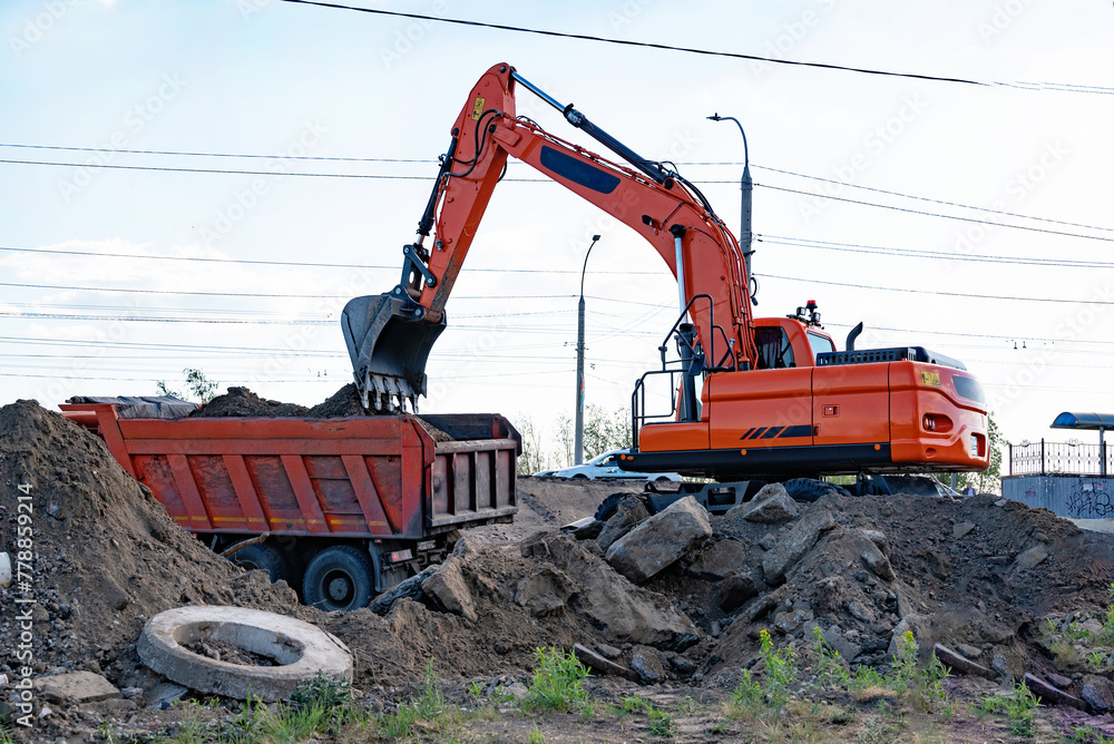 Excavator during earthmoving at open pit on blue sky background ...