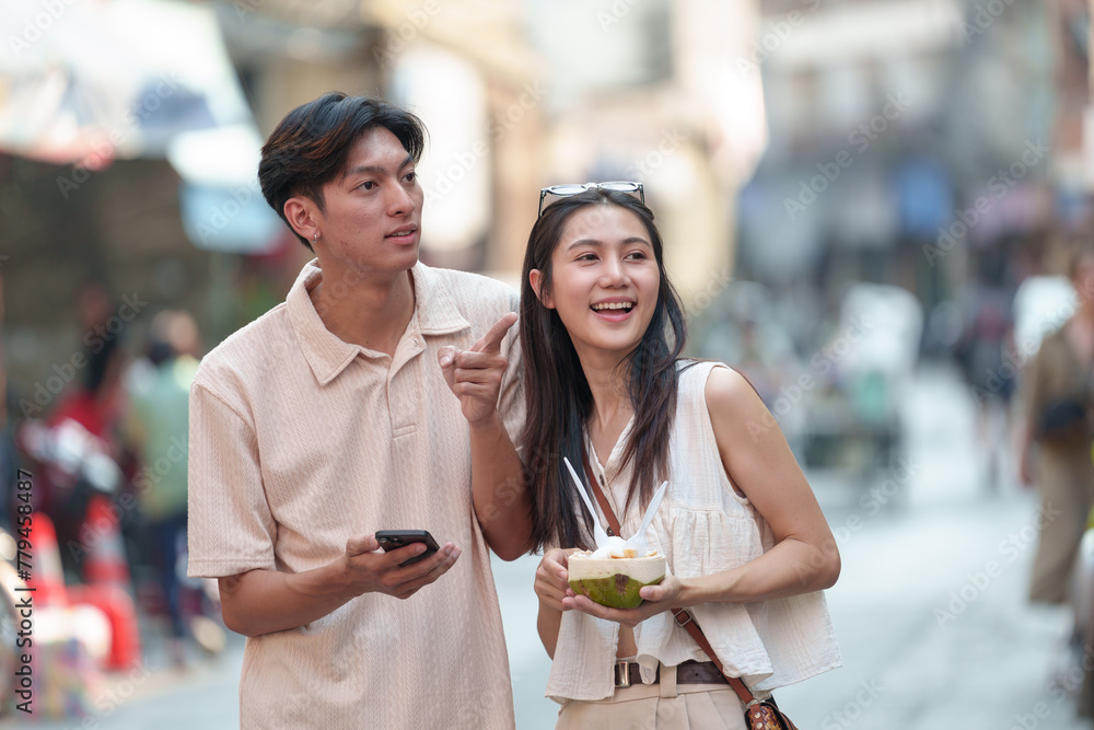 A cute and happy Asian tourist couple tours the old town market using ...