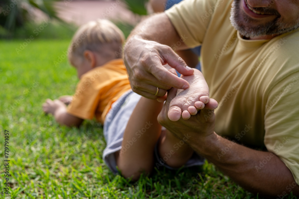 family and love concept - young father tickling his little son in park ...