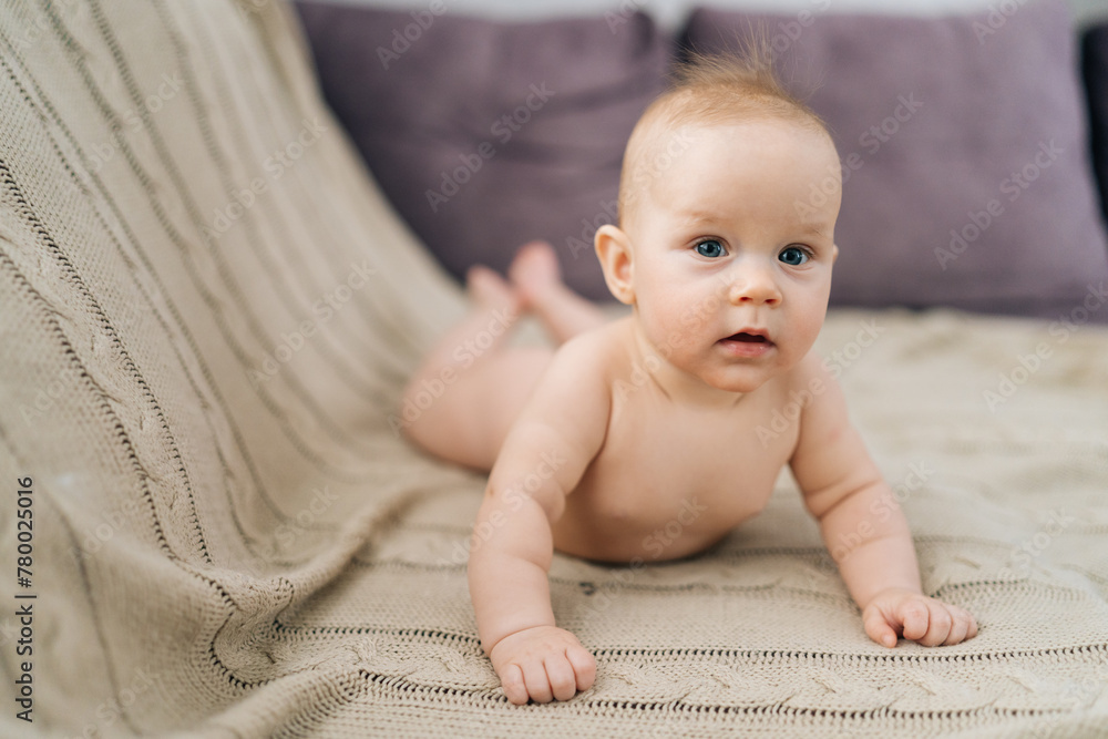 Curious cute little baby child lying on stomach on bed, interestingly ...