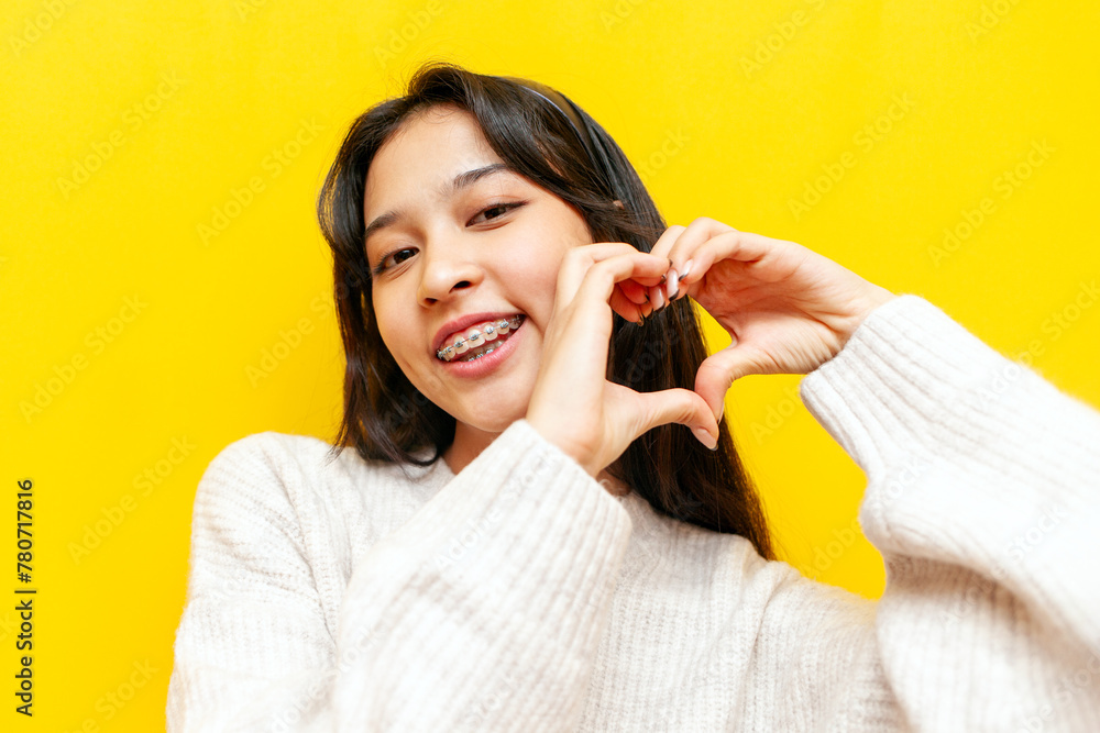 young asian woman with braces showing heart with hands and smiling on ...