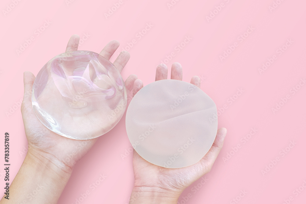 Silicone implant breast augmentation on space pink studio background ...