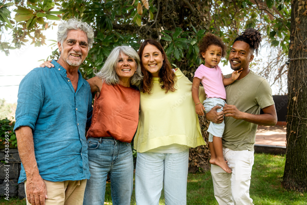 Happy diverse multigenerational family embracing in a sunny garden, a ...
