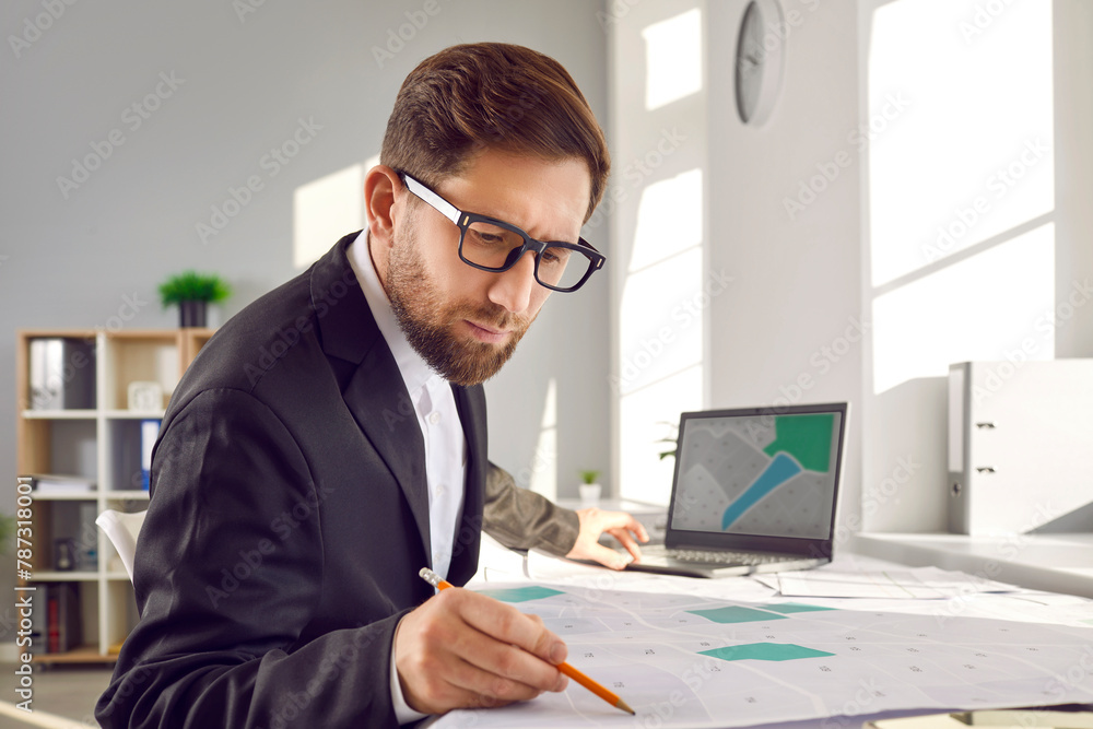 Professional surveyor in suit and glasses sitting at office table ...