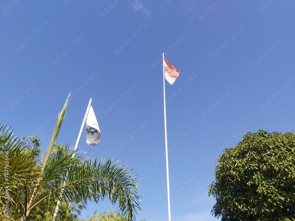 the red and white flag under a cloudy blue sky in the afternoon. The ...