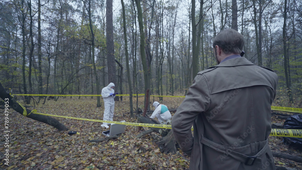 Detective overseeing evidence collection at a forest crime scene ...