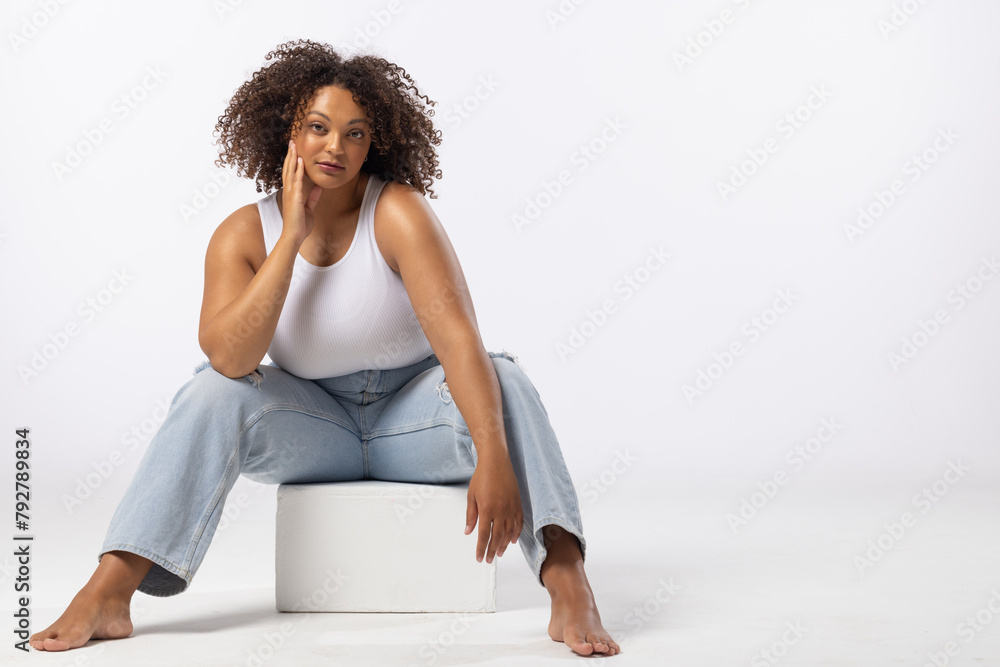 Biracial plus-size child model touches her face thoughtfully on a white ...