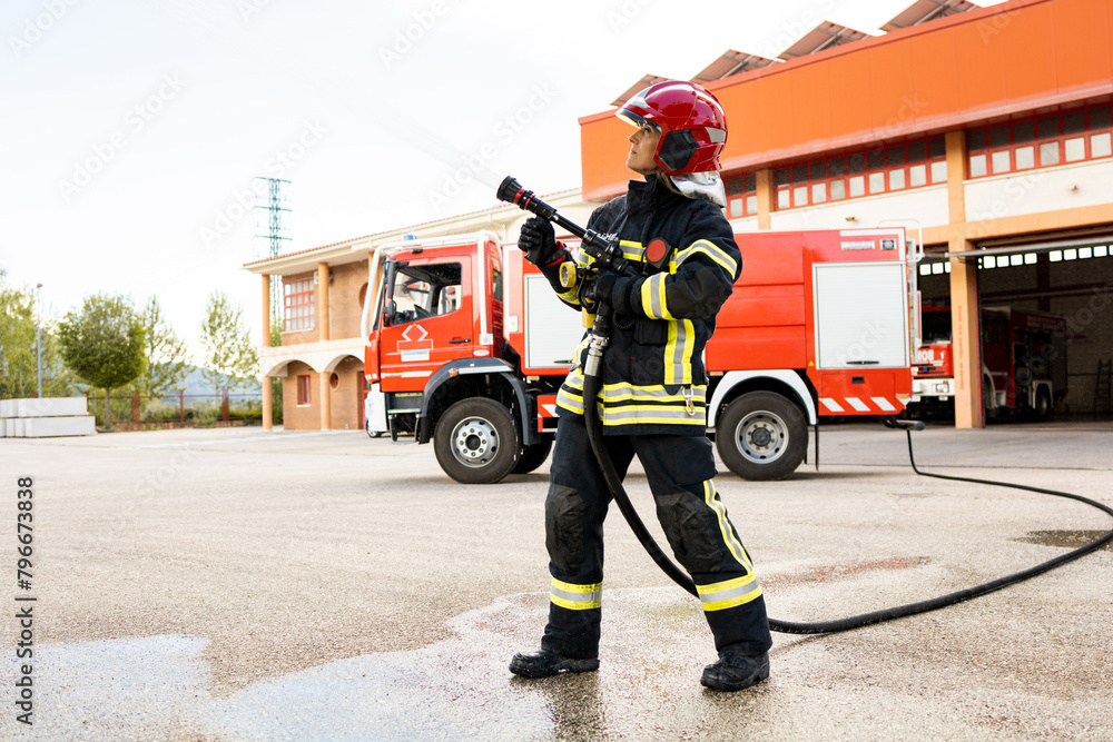 An adult Caucasian woman works as a firefighter at a fire station ...