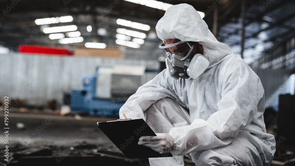 Workers in protective suits inspect chemicals in an old factory ...