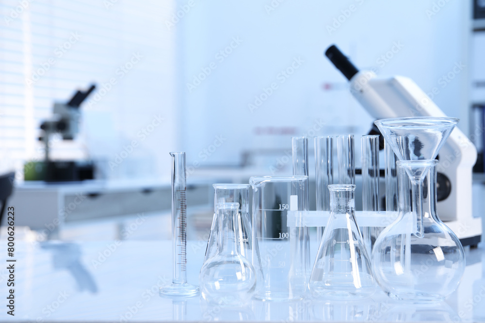 Laboratory analysis. Different glassware and microscope on white table ...