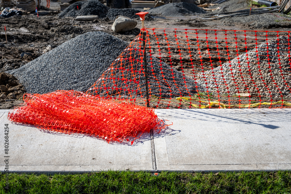 Fresh new orange safety fencing being set up next to sidewalk around a ...