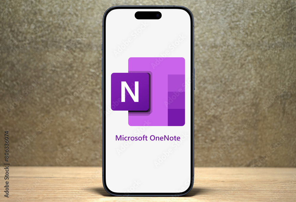 OneNote logo displayed on a modern smartphone standing on a desk, note ...