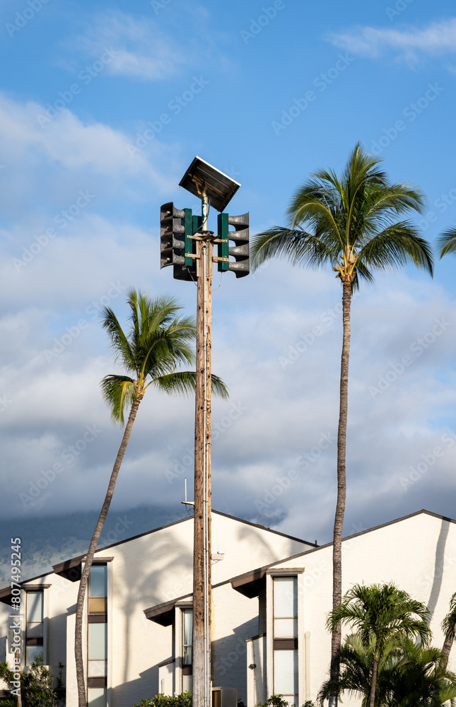 Topical setting with solar powered tsunami sirens in front of apartment ...
