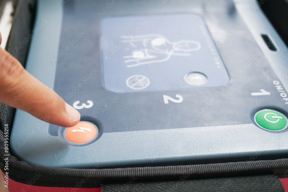 pressing the AED's shock button to deliver an electric shock to a heart ...