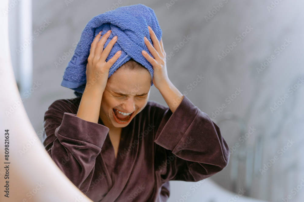 Young beautiful woman screaming and wearing shower towel after bath ...