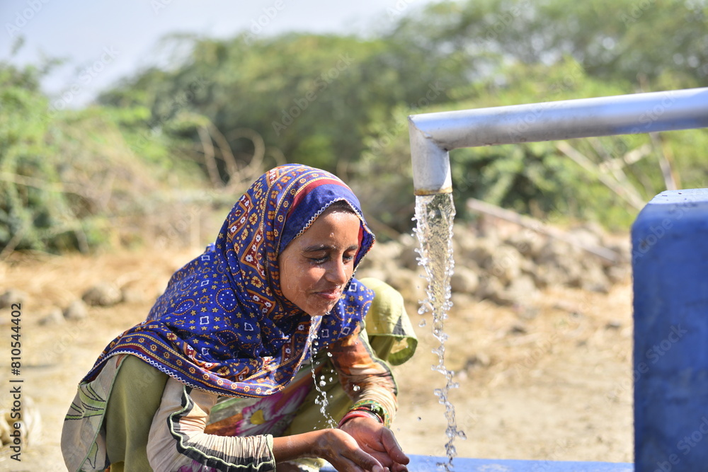 Child Drinking from a Hand Pump. Young Pakistani girl drinking clean ...