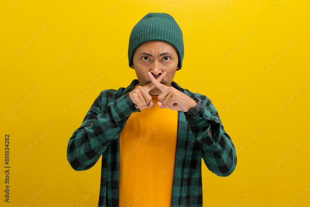 Serious young Asian man, dressed in a casual shirt and wearing a beanie ...