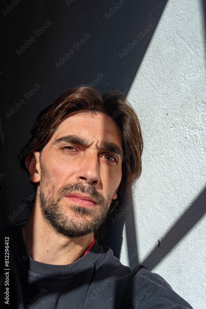 rostro de joven con su cabeza sobre la pared iluminada detras de una ...