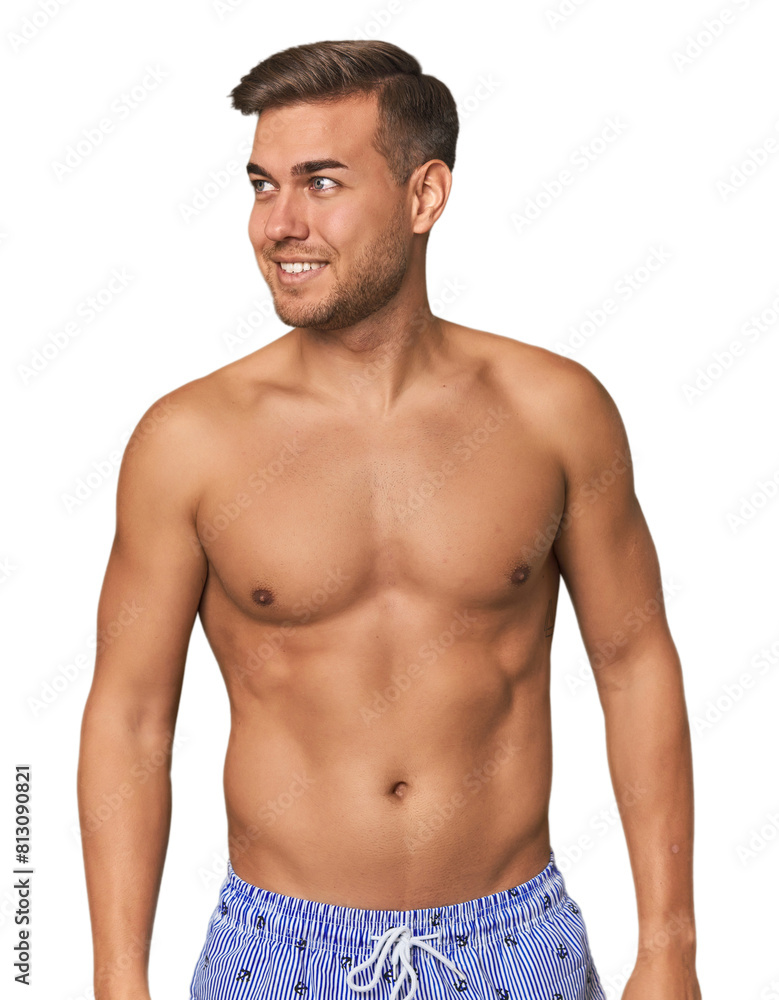 Shirtless young man in swimsuit against a studio backdrop, embodying ...