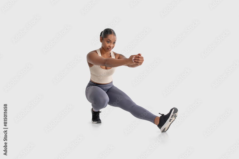 African American woman is shown doing a squat exercise on a plain white ...