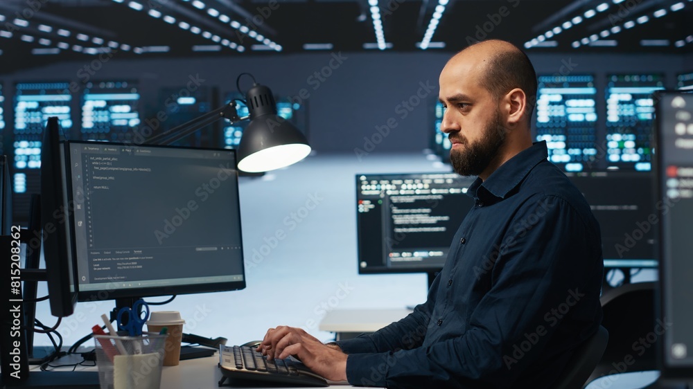 Software developer programming in high tech facility with server rows providing computing ...