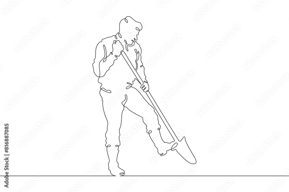 A man in work clothes digs with a shovel. The male farmer is digging. A ...