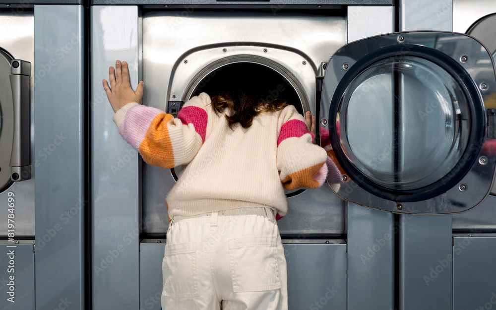 Preteen girl looking inside the washing machine Stock Photo | Adobe Stock