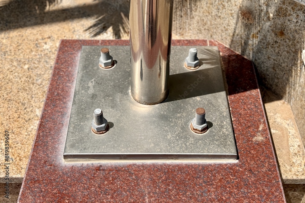 Metal pillar fastened to basement with different anchor bolts and nuts ...
