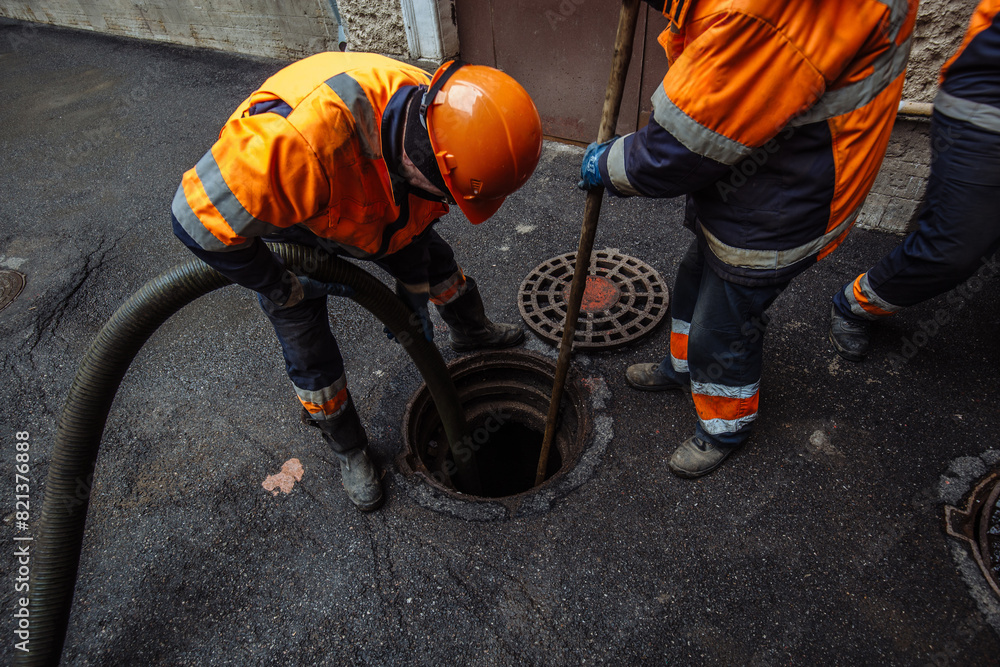 Sewer workers cleaning manhole and unblocking sewers the street ...