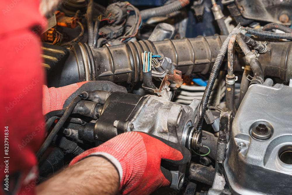 The mechanic is refitting the distributor in the garage. Replacing a ...