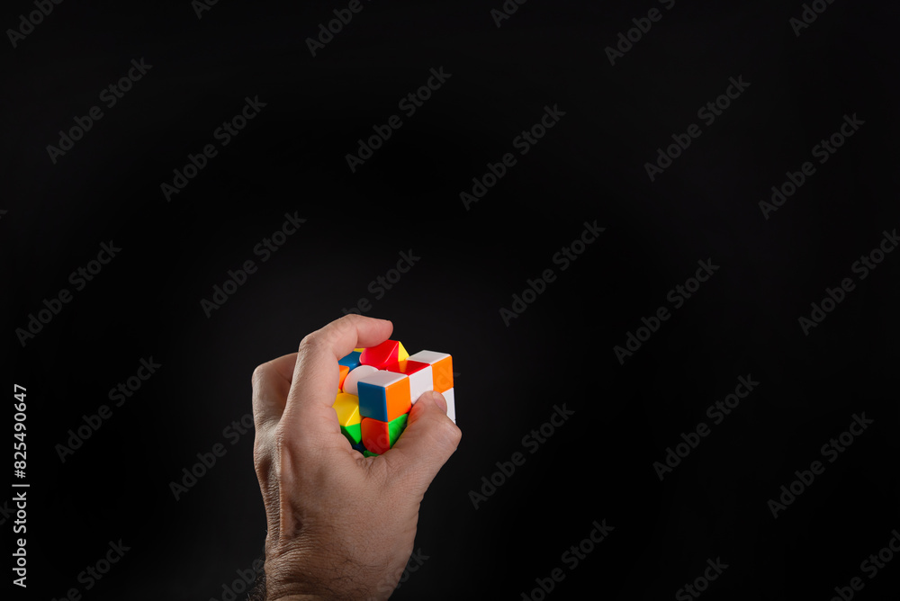 Rubiks cube in a persons hands, portrait, black background. Man holding ...