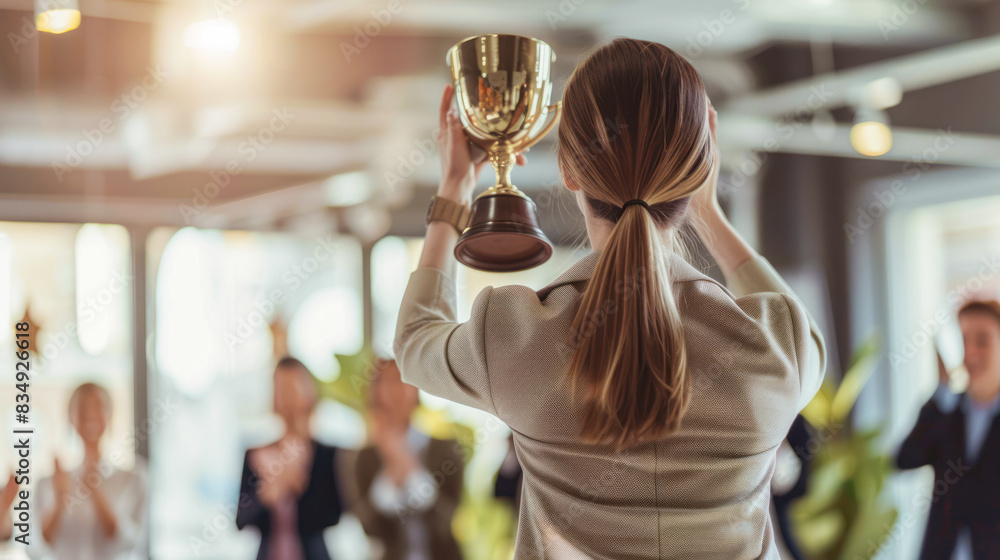Businesswoman in suit holding a golden trophy cup with both hands ...