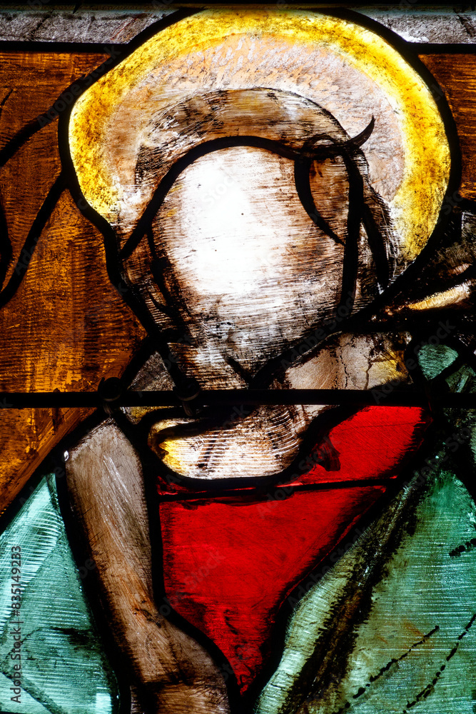 An ancient stained glass window depicting a faceless saint in a church ...