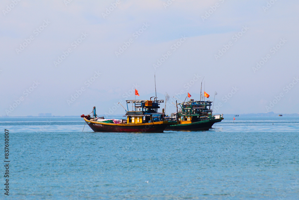 Photograph of traditional Asian fishing boats floating in the sea near ...